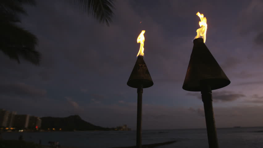 Torches With Fire And Flames Burning In Hawaii Sunset Sky By Palm Trees ...