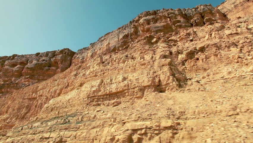 Medium Wide, Close-up Drive-by Of The Desert Cliff Face From The Bottom ...