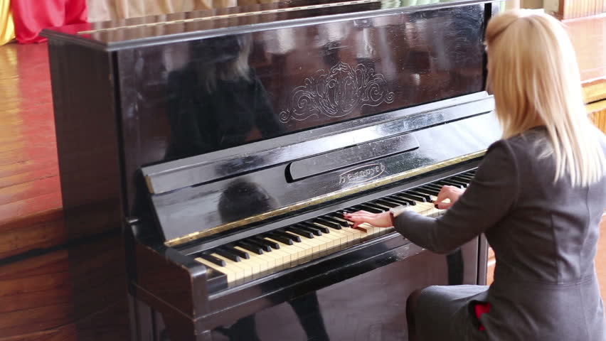 Girl Playing The Piano. A Girl With Blond Hair In A Gray Dress Playing ...