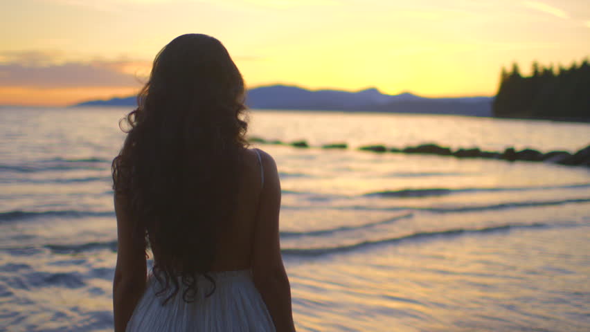 Woman Looking At Sea Sunset. Back View Of Woman Standing On Beach At ...
