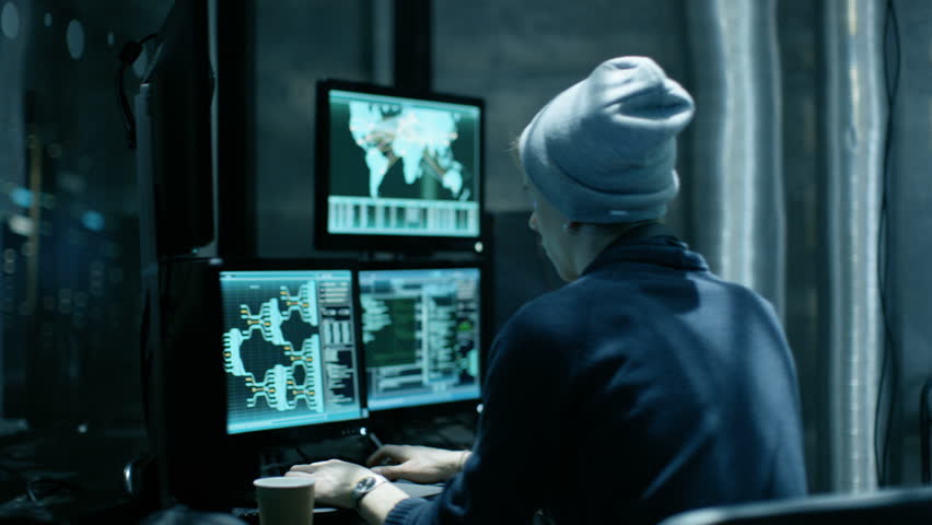 Two Hackers In Hoods Work On A Computers With Maps And Data On Display ...