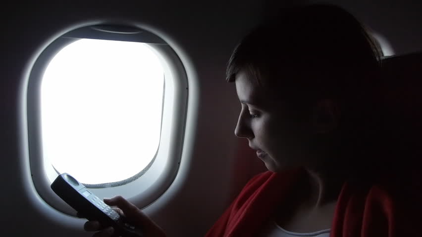 Young Woman Is Using A Smartphone Inside An Airplane Next To A Window ...