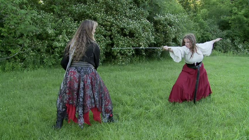 Two Women In Medieval-style Costumes Fight With Swords On A Grassy ...